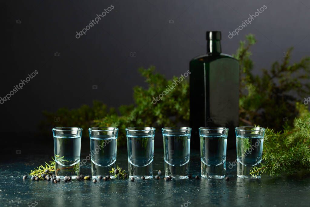 Ginebra azul y ramas de enebro en una mesa azul oscuro. Vasos de ...