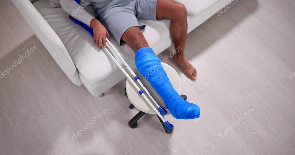 Joven con la pierna rota sentado en el sofá 2023