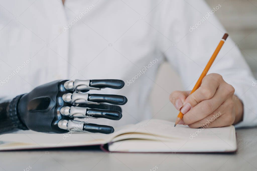 Close up of cyber arm and healthy limb on the notebook. Handicapped ...
