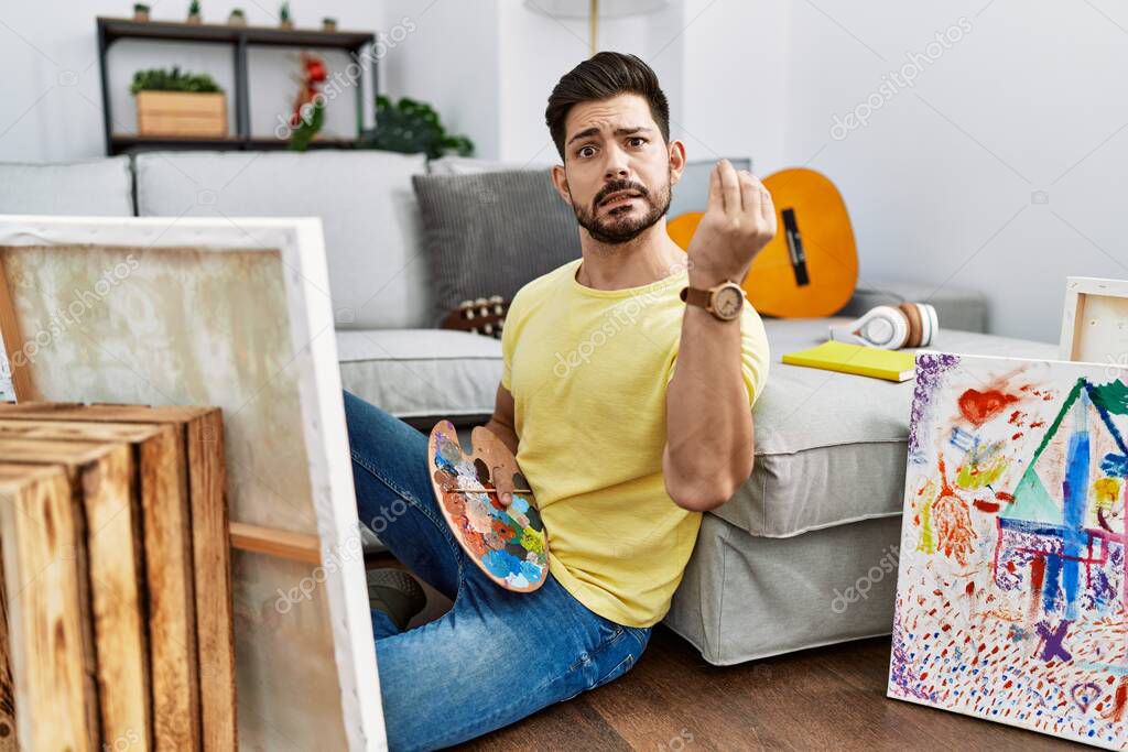 Joven con barba pintando lienzo en casa haciendo gesto italiano con la ...