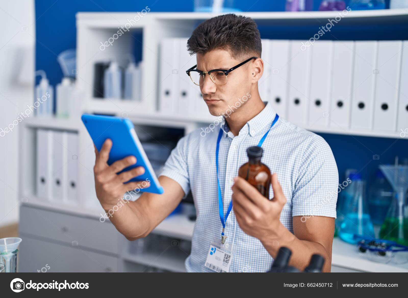 Young Hispanic Man Scientist Using Touchpad Holding Bottle Laboratory Stock Photo by ...