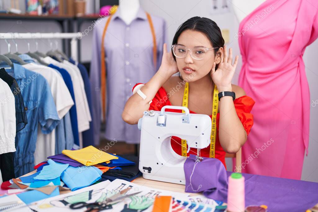 Mujer joven hispana modista diseñador utilizando la máquina de coser ...