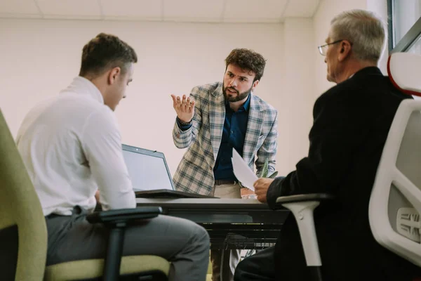 Disappointed and angry boss overlooking and correcting his employees at ...