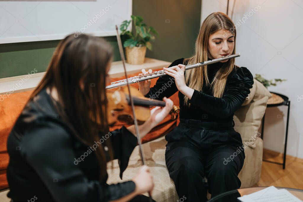 Dos mujeres jóvenes, una tocando la flauta y la otra el violín, practicando música juntas en un ...