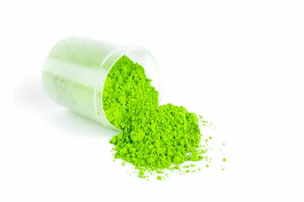 A bright green powder spills from a clear container, contrasting ...