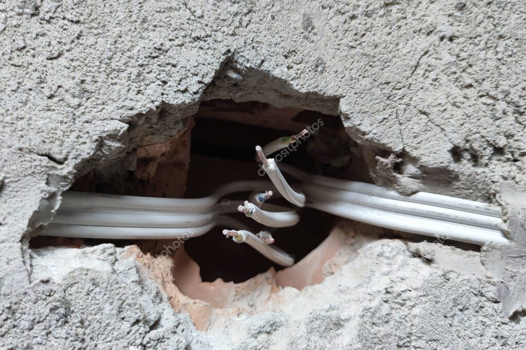 bare electrical wires in a concrete wall, installation of an electrical ...
