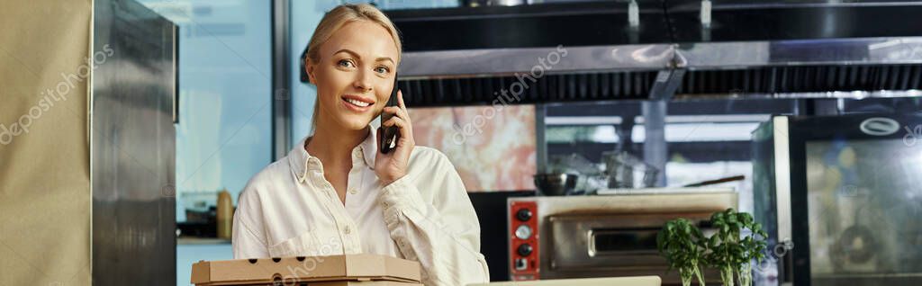 sonriente rubia gerente de café con cajas de pizza hablando en el ...