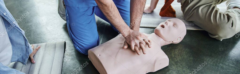 first aid seminar, hands-on learning, cropped view of paramedic showing chest compressions on ...