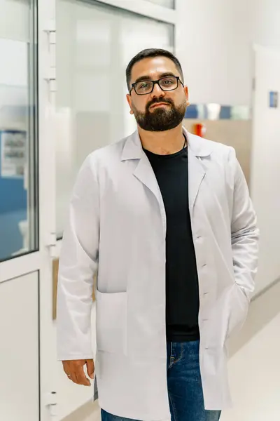Doctor in lab coat in hospital hallway. A healthcare worker stands ...
