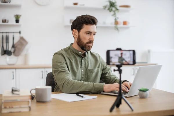 Active male influencer using modern smartphone and tripod for live ...