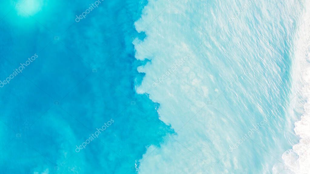 Vista superior de agua azul claro con arena blanca. Las olas levantan ...