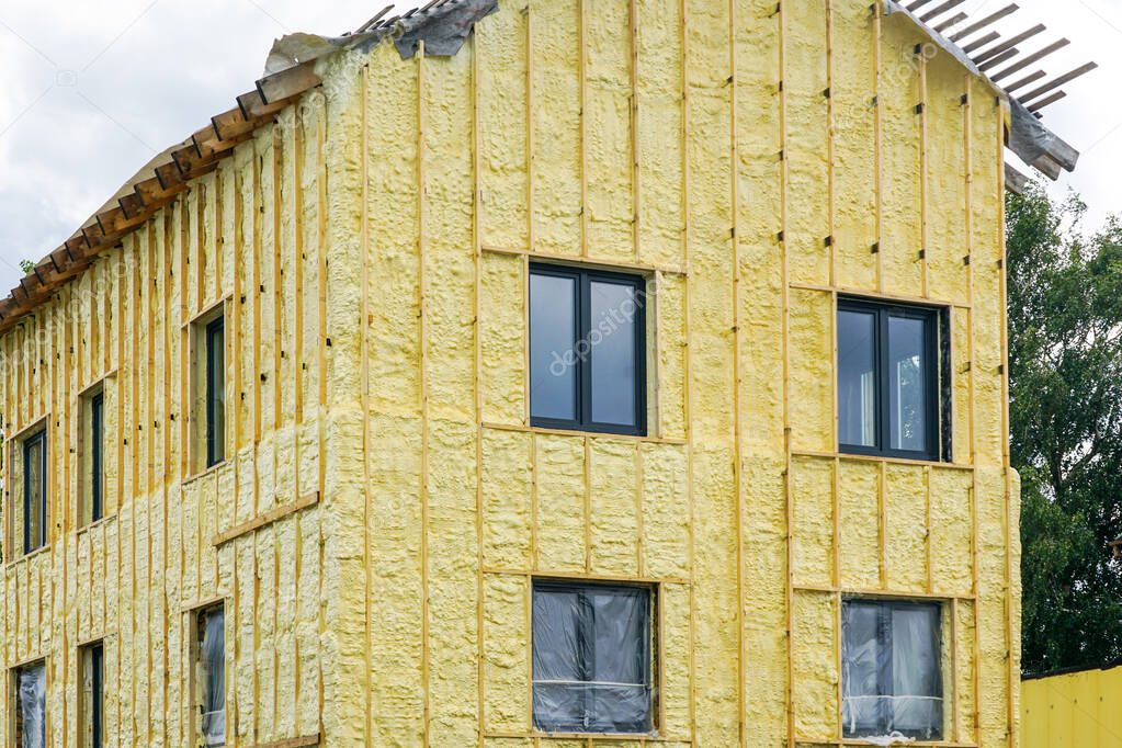 La fachada de la casa residencial rociada con una capa de espuma de aislamiento térmico de ...