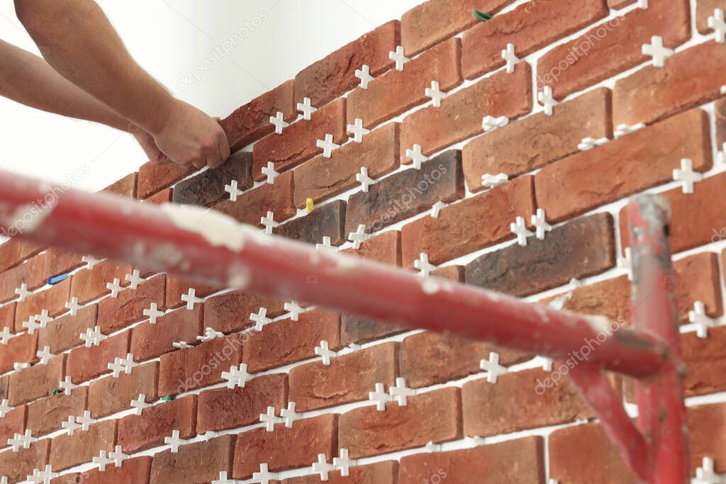 Constructor profesional pegando ladrillo decorativo en la pared, primer ...