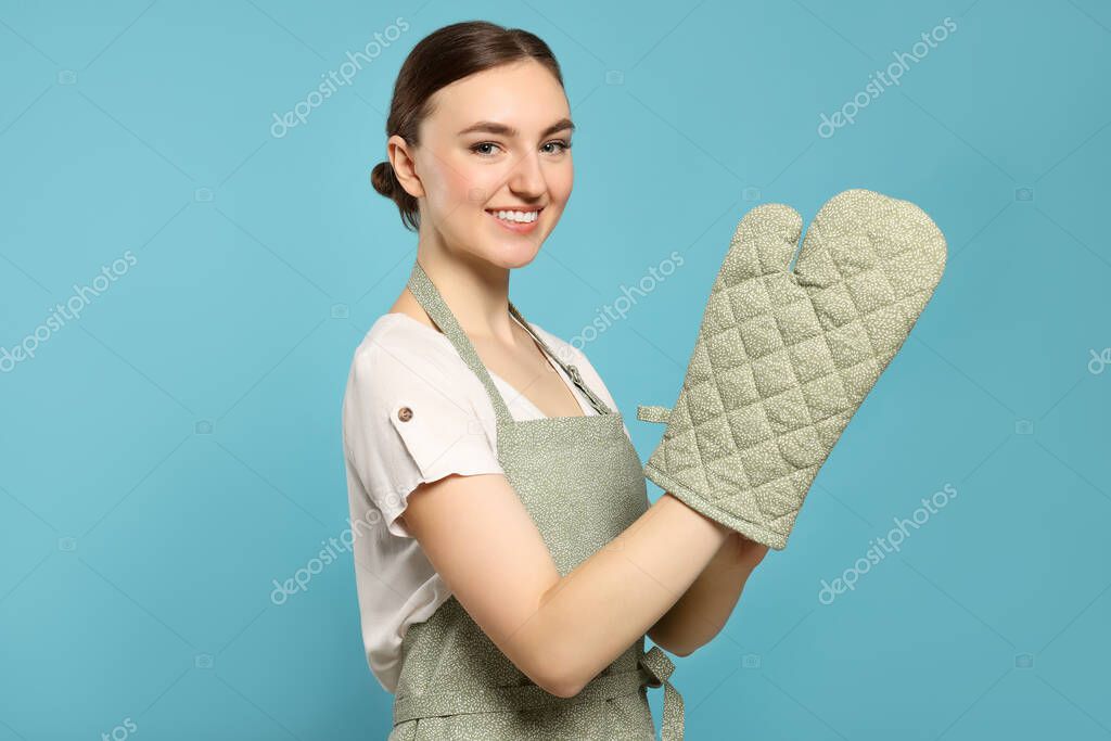 Beautiful young woman in clean apron with pattern and oven glove on ...