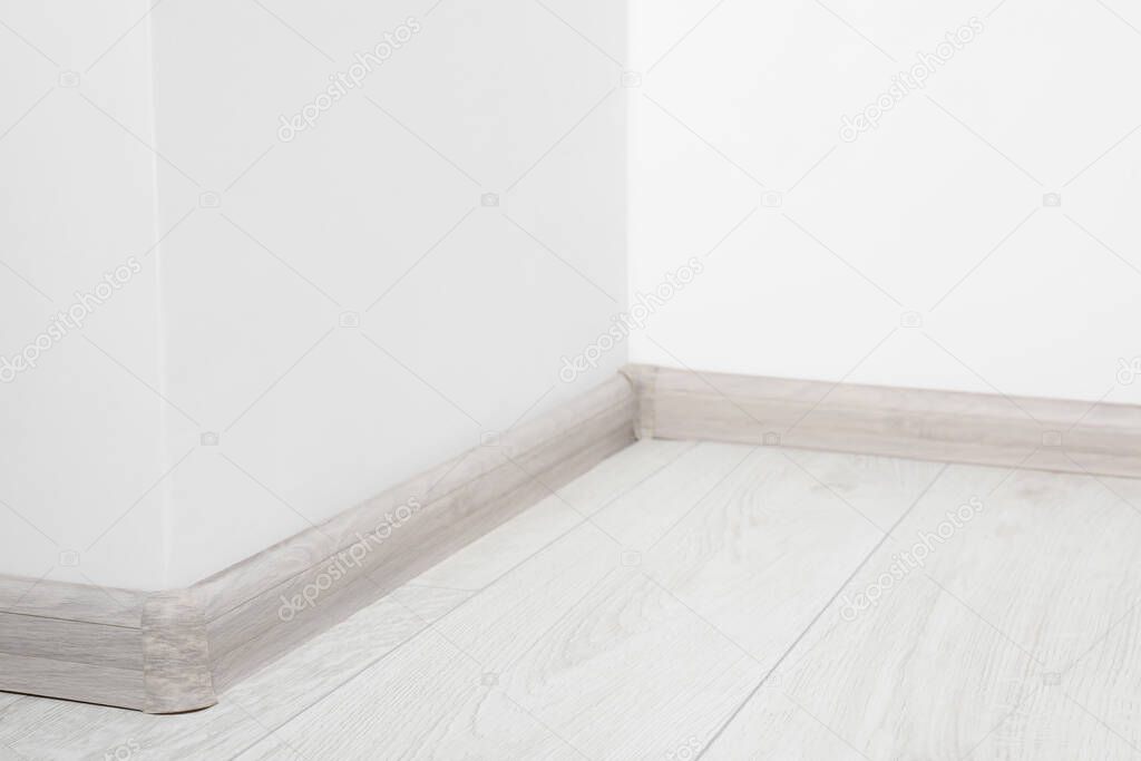 Plinto de madera con conectores en suelo laminado cerca de pared blanca ...