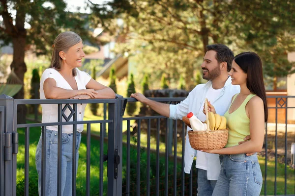Friendly relationship with neighbours. Young couple with wicker basket ...