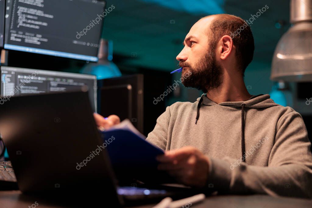 Desarrollador web analizando el código fuente con papeles y computadoras, tomando notas y ...