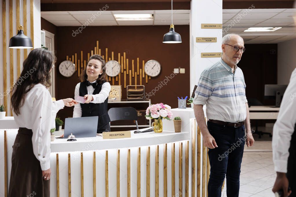 La recepcionista femenina ayuda a una mujer mayor en la recepción a ...