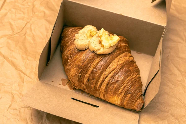 Fresh croissant from a pastry shop in a cardboard box made of recycled ...