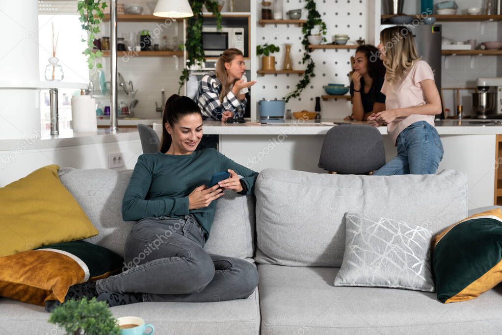 Mujer joven sentada sola aislada de un grupo de amigos, no quiere escuchar chismes y charlas ...