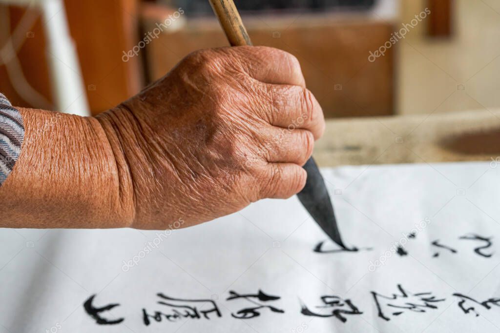 Un viejo calígrafo chino está escribiendo caracteres de caligrafía ...