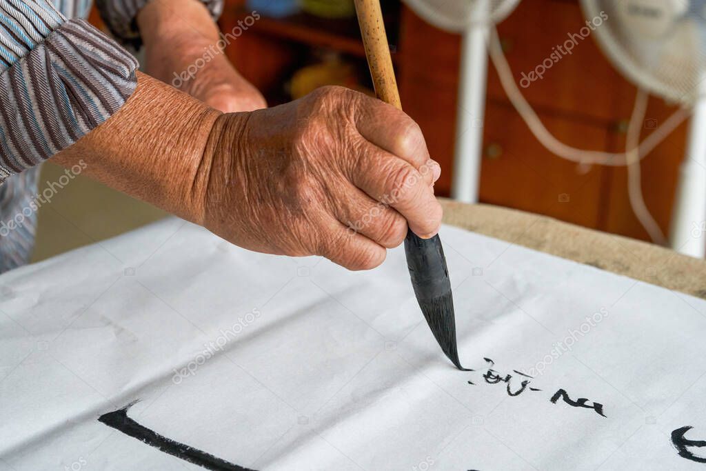 Un viejo calígrafo chino está escribiendo caracteres de caligrafía ...