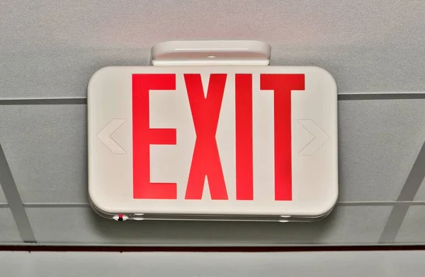 Exit sign isolated on a ceiling indoors in a building. Commonly posted ...