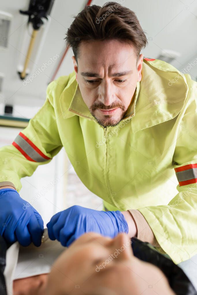 Paramédico en guantes de látex quitándose la ropa del paciente borroso ...