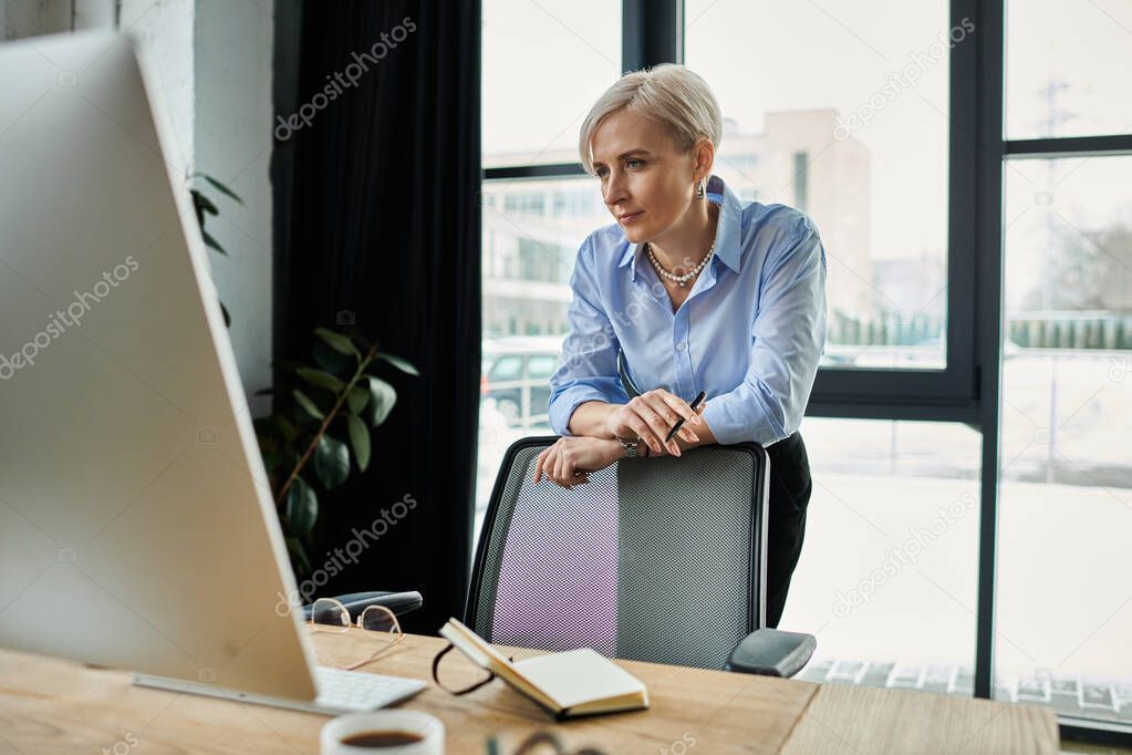 Una mujer de negocios de mediana edad con el pelo corto trabaja diligentemente en su escritorio ...