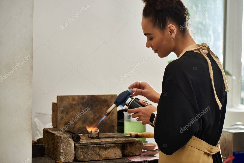 Un artesano utiliza cuidadosamente una antorcha para derretir el metal ...