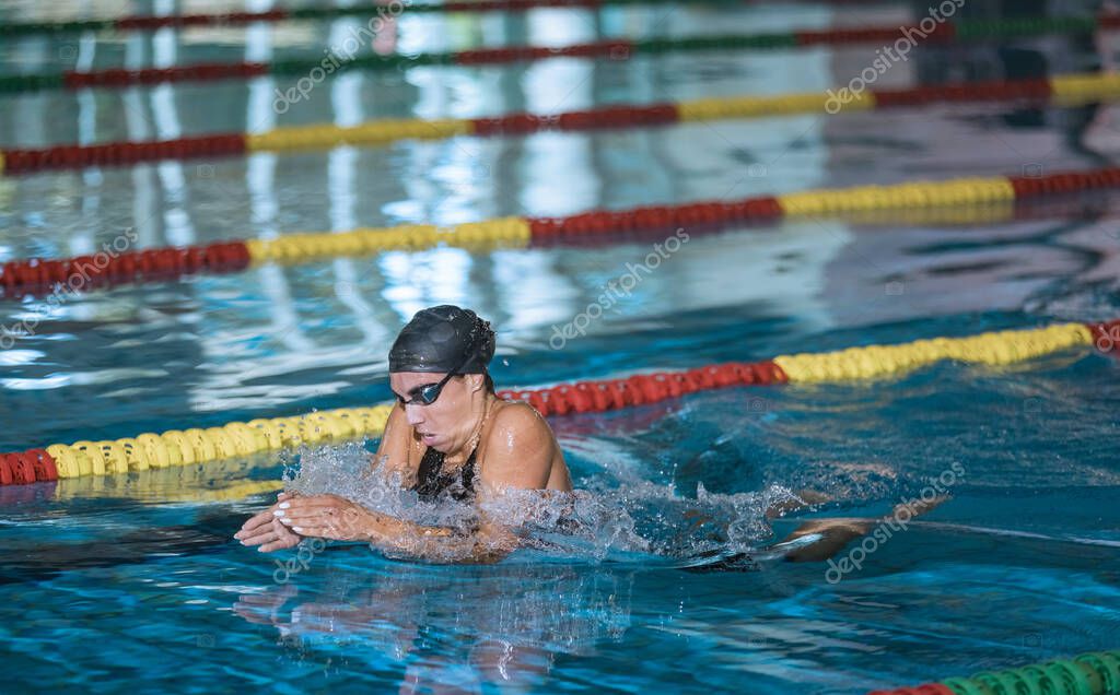 Atleta femenina nadando en estilo de pecho en el carril de la piscina ...