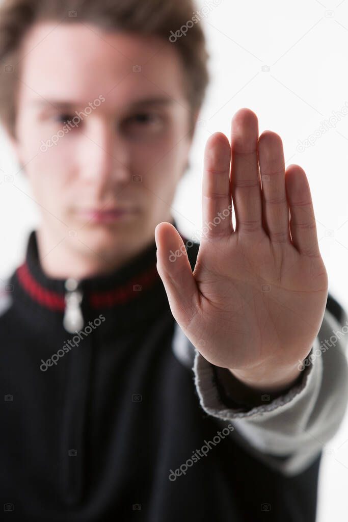 determinado joven levanta la mano señalando "alto". Está tomando una ...