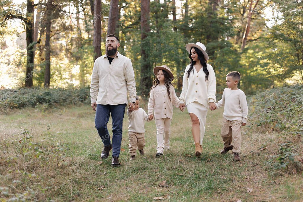 Young mother, father with daughter and sons are walking, having fun in autumn forest. Family ...