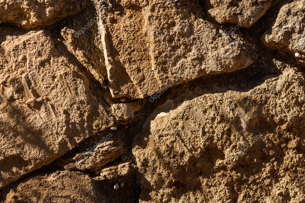 La superficie rugosa de una pared de piedra revela texturas intrincadas ...