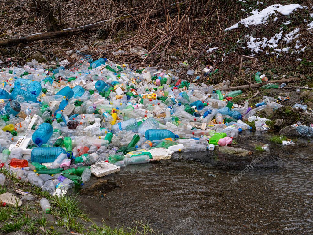 CLOSE UP: Floating pile of various plastic bottles caught at the edge ...