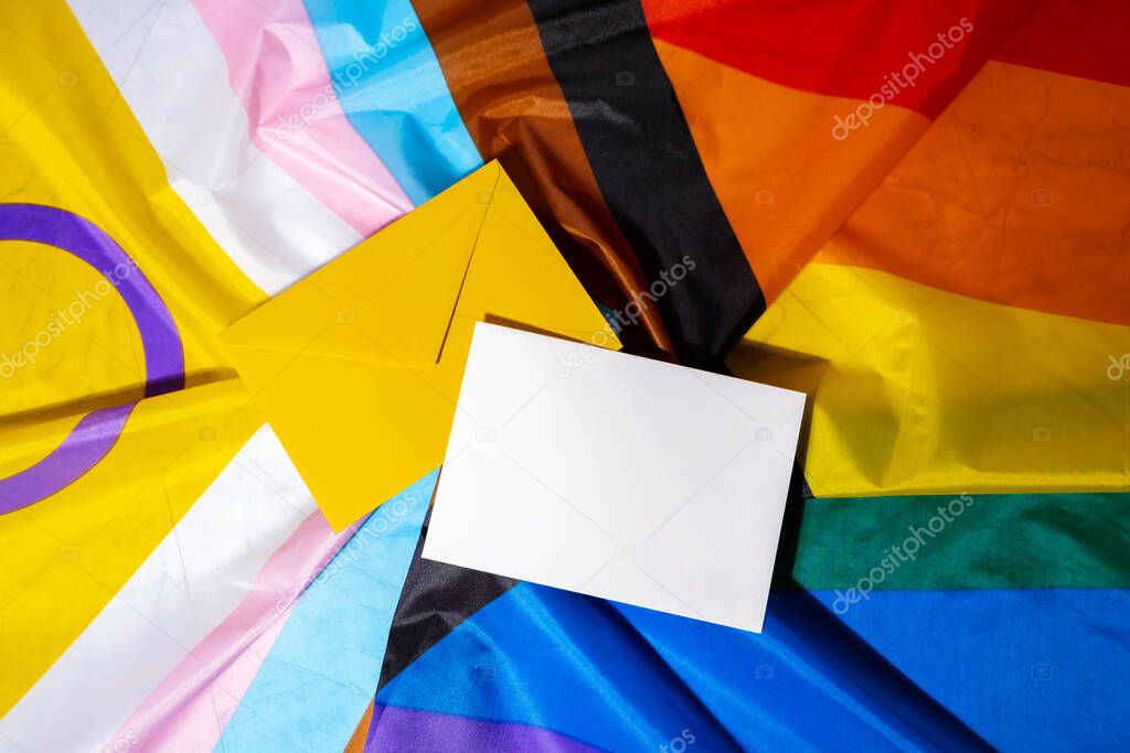 Empty paper blank on Rainbow LGBTQIA flag made from silk material. Mock ...