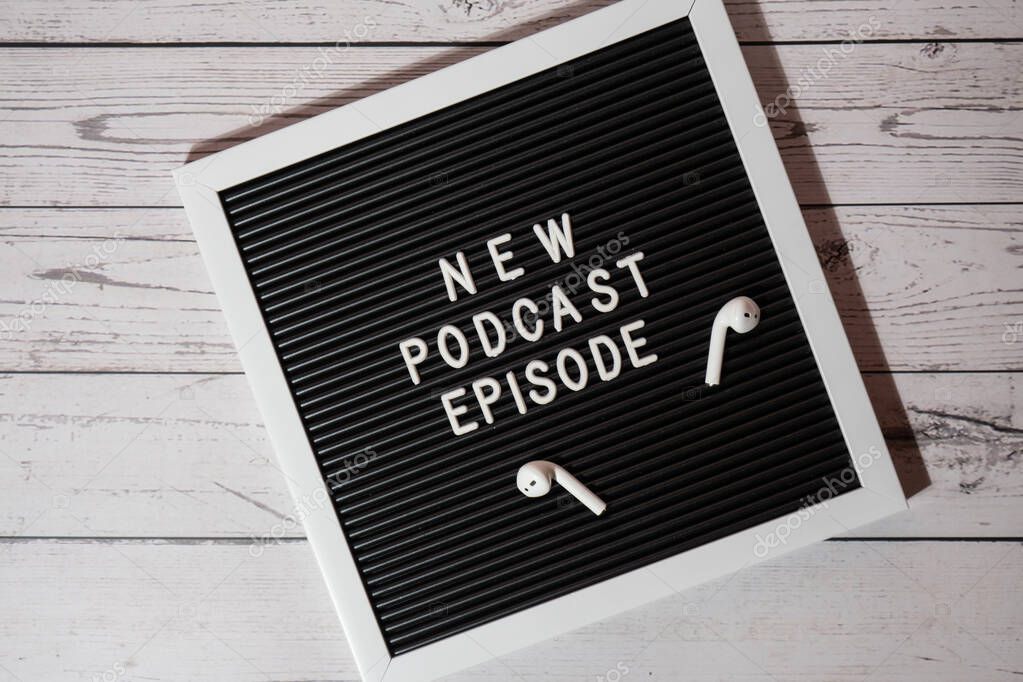 Anuncio Tablero de cartas con texto NEW PODCAST EPISODE en mesa de madera con auriculares ...