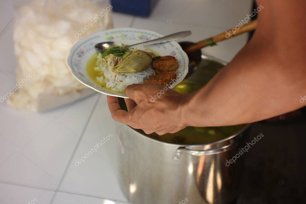La persona que sirve sopa de pollo en un plato está sosteniendo una ...