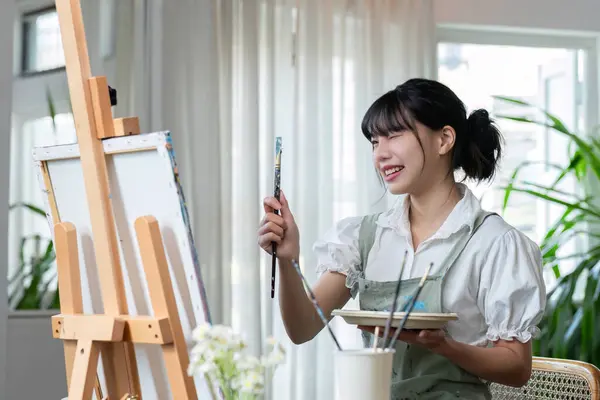 Young female artist works on abstract acrylic painting on canvas in art ...