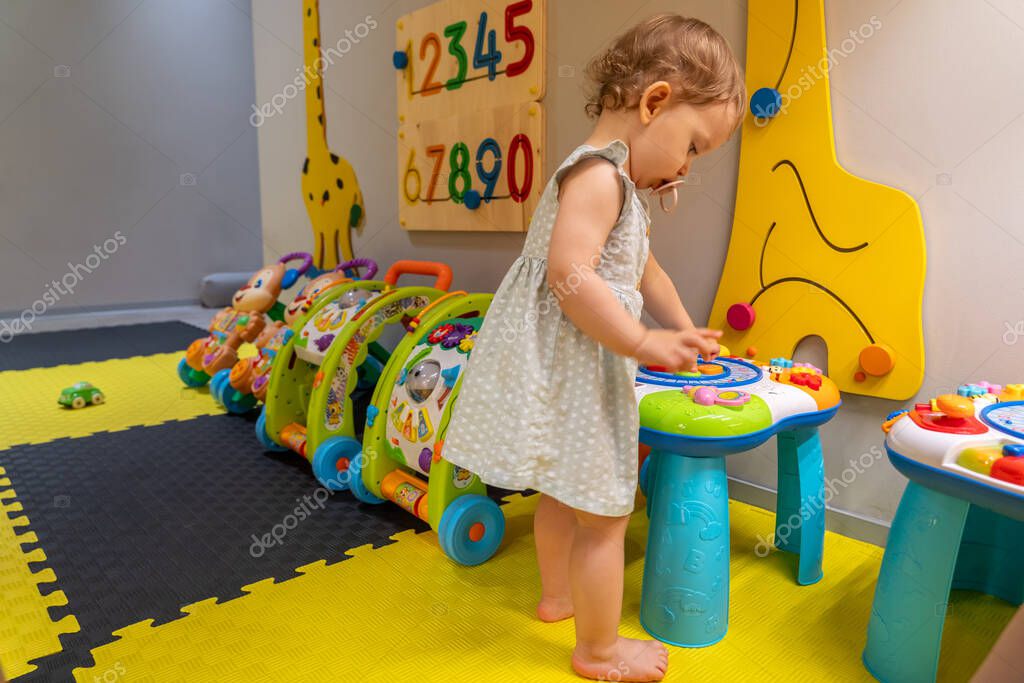 Niño explorando una colorida mesa de actividades en una atractiva sala ...