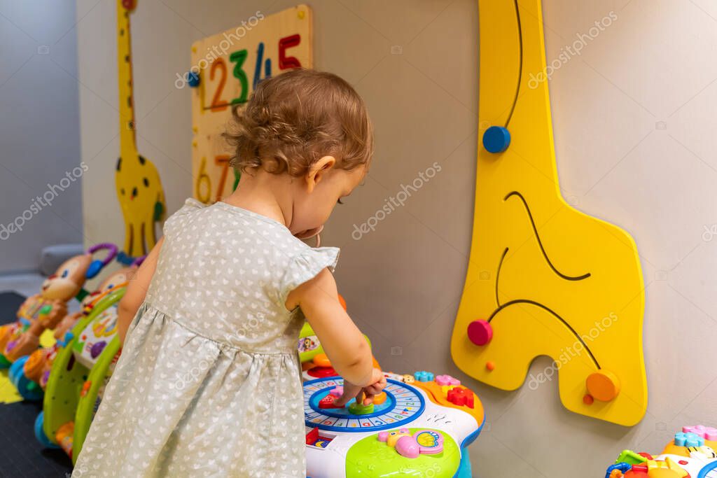 Niño explorando una colorida mesa de actividades en una atractiva sala ...