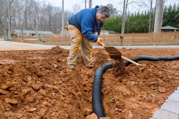 When rain is heavy worker digs trench to lay drainage pipes for ...