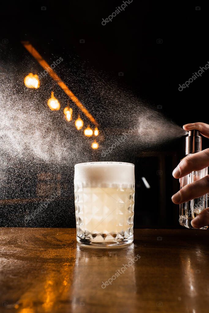 El camarero está rociando whisky sobre el cóctel de penicilina. Cóctel ...