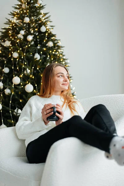 Smiling young female enjoy New Year winter holiday at home, dreaming or ...