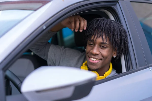 Side view portrait of a happy african young man sitting inside a car ...