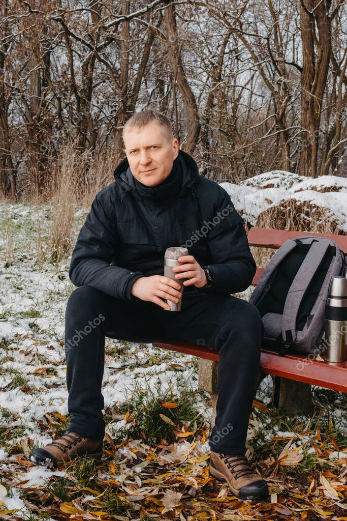 Winter Serenity: 40-Year-old Man Enjoying Tea on Snow-Covered Bench in ...