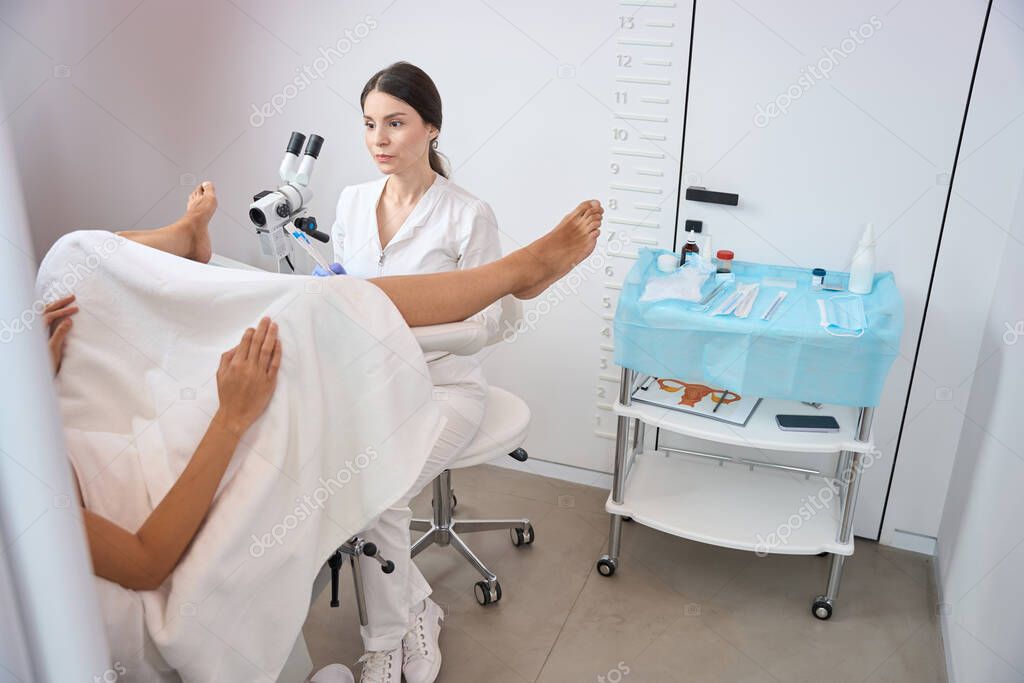 Ginecóloga femenina está sentado y haciendo un examen de los órganos ...