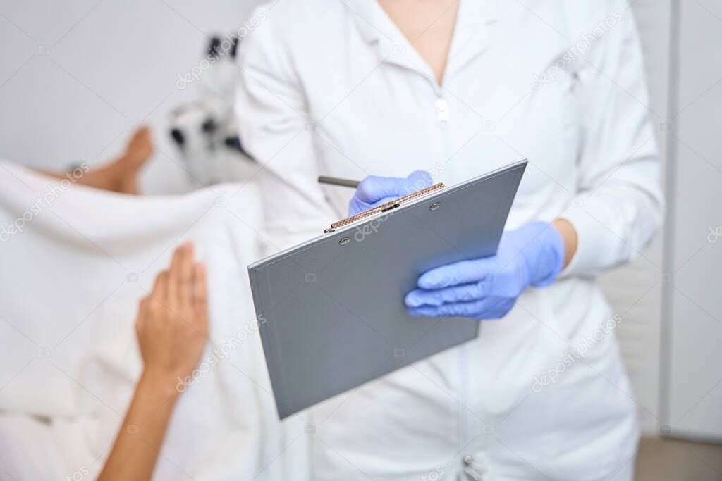 Ginecóloga mujer escribe las quejas de la paciente en la historia clínica 2023