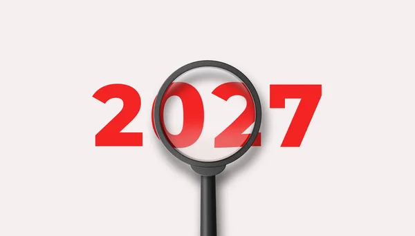 Magnifying glass magnifies the year 2027 on white background. Focusing ...