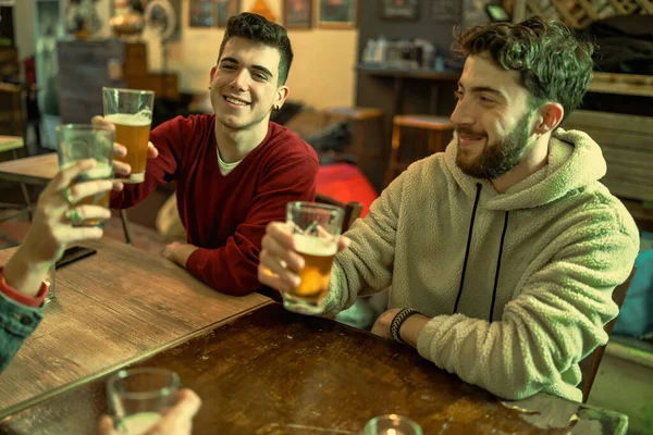 Dos jóvenes, vestidos con un atuendo acogedor, comparten un momento alegre mientras levantan sus ...
